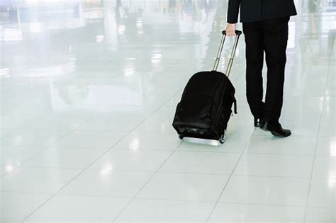 공항 내부의 여행 가방을 들고 걷는 동안 휴대 전화로 전자 메일을 확인하는 사업가 가방에 대한 스톡 사진 및 기타 이미지