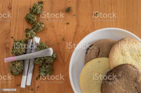 압 연된 합동을 가진 마리화나 새싹과 나무 테이블에 마리화나의 수 제 쿠키 접시의 더미 대마초와 쿠키의 아침 식사입니다 가정