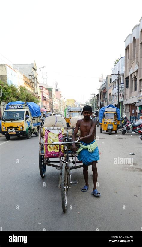 A Tamil Man Dressed In Lungi Pushing His Loaded Transport Rickshaw In