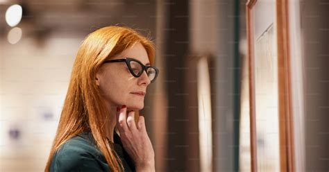 안경을 쓴 빨간 머리의 젊은 여자가 그림을 보고 갤러리에서 예술을 즐기고 있다 사진 Unsplash의 초상 이미지