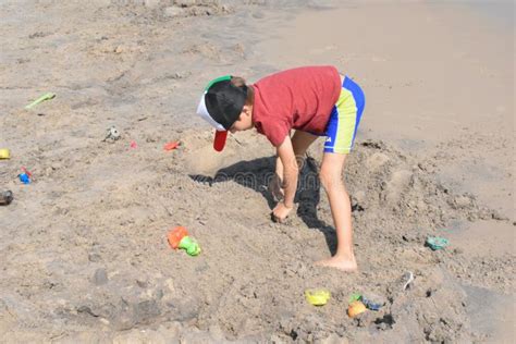 Niño Jugando En La Arena De La Playa Niño Ardiendo Bajo La Arena Caliente Foto de archivo