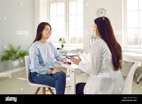 Satisfied Female Patient Uses Pulse Oximeter While Talking To Doctor At