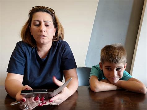 Premium Photo Son Sitting By Mother Using Phone At Table