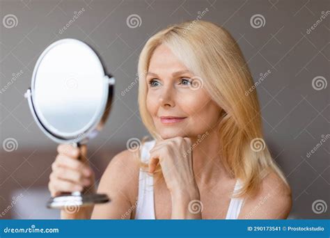 Portrait Of Beautiful Mature Woman Looking In Magnifying Mirror And
