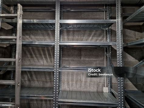 회색 카펫이 깔린 빈 하얀 방과 벽 전체를 따라 선반이 있습니다 탈의실의 물건 상품 옷을 보관하고 문서 파일을 보관하기 위한 금속 홀더 및 라미네이트 선반 사무실 비즈니스