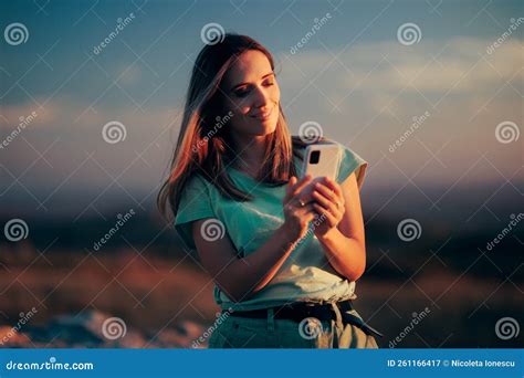 Woman Holding Her Phone Exploring Nature At Golden Hour Time Stock