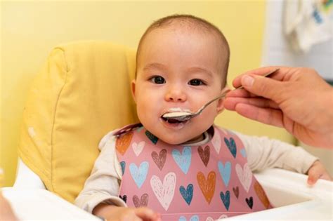 Primer Plano De Un Bebé Comiendo Cereal Y Sentado En Una Silla Alta