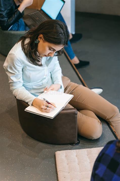 Above Photo Of Brunette Girl Writing Notes Down In A Notebook During