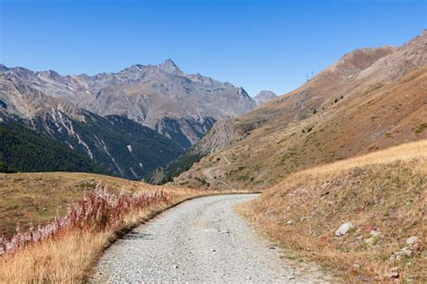 이탈리아 아오스타 계곡의 그란 파라디소 국립공원에 있는 가을 시든 풀로 무성한 화강암 산의 경사면을 따라 놓인 잘 포장된 자갈 넓은 길 0명에 대한 스톡 사진 및 기타