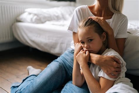 Retrato De Una Niña Triste Mirando A La Cámara Y Una Madre Cariñosa