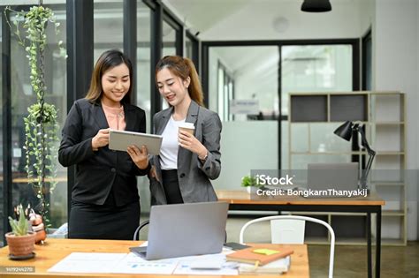 태블릿 화면을 함께 바라보는 두 명의 쾌활하고 아름다운 아시아 사업가 20 24세에 대한 스톡 사진 및 기타 이미지 20