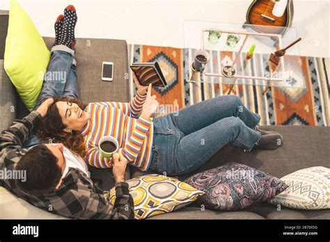 Happy Couple Using Tablet While Relaxing On Sofa At Home Young