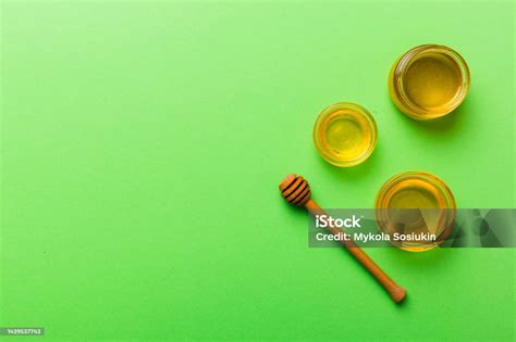 색깔있는 배경에 나무 이슬비가 달린 꿀의 유리 항아리 꿀 냄비와 디퍼 높은 위 위쪽 보기 복사 공간 1위에 대한 스톡 사진 및