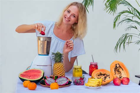 신선한 주스 믹스 과일을 가진 젊은 행복한 여자는 따뜻한 기후에서 하얀 배경의 여름 열대 휴가에 과즙 짜는기구 스무디 항아리에 건강한 음료를 만드는 신선한 수확 30 34