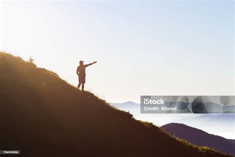 산꼭대기에 있는 남자 감정적 인 장면 배낭을 들고 산 꼭대기에 손을 들고 산의 경치를 즐기는 청년 산 꼭대기에 있는 등산객