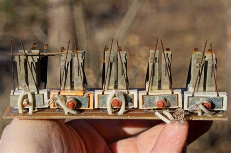 Hand Holding An Old Brown Microcircuit With A Row Of Gray Metal Parts
