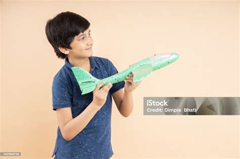 베이지색 스튜디오 배경에 고립된 비행기 장난감을 손에 들고 있는 행복한 장난기 많은 인도 소년 아이 복사 공간 아이에 대한 스톡 사진 및 기타 이미지 Istock