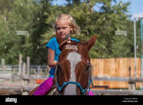 Young Blonde Girl Riding Horse Looks Directly In Camera Smiling