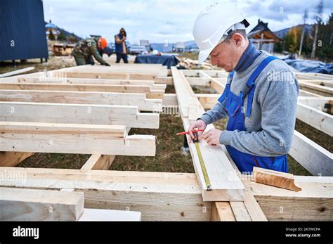 Man Worker Building Wooden Frame House On Pile Foundation Carpenter