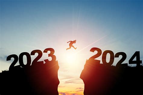 2024년 메리 크리스마스와 새해 복 많이 받으세요 구름 하늘과 햇빛이 있는 2023절벽에서 2024년 절벽으로 점프하는 실루엣