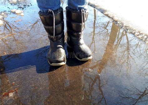 Las Botas De Goma Negras De Las Mujeres En Un Charco En Primavera