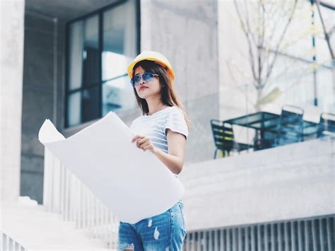 Premium Photo Female Engineer Holding Blueprint Against Building
