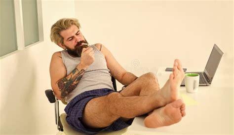 Barefoot Man Smoking Cigarette And Watching Film On Laptop Screen At