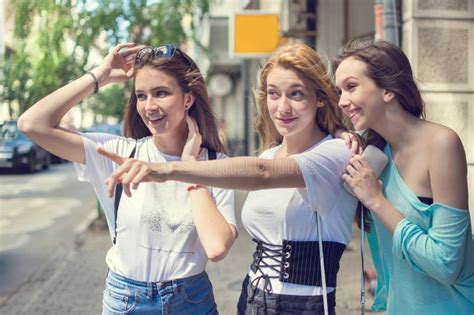 Three Teenage Girls Looking At Something Together Outdoors Stock Image