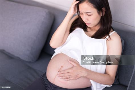 임산부는 자궁에 있는 아이에 대해 염려하는 마음으로 앉아 있습니다 임신에 대한 스톡 사진 및 기타 이미지 임신 두통