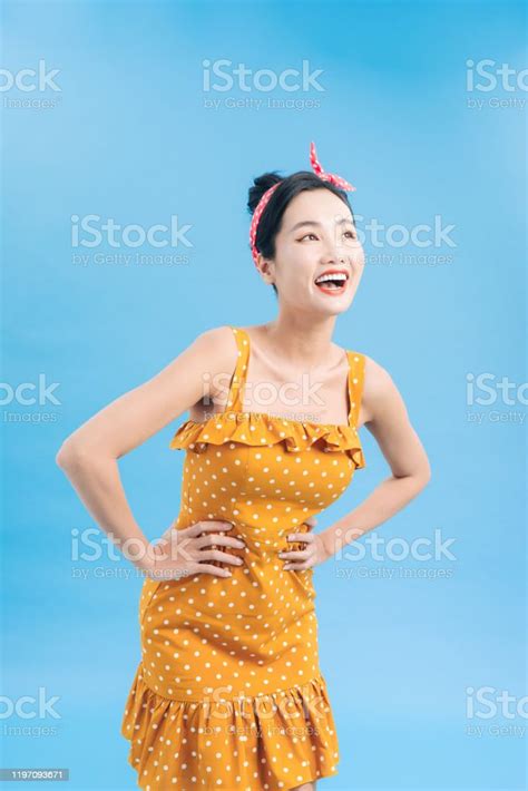 파란색 배경에 서 물방울 무늬 드레스를 입고 포즈를 취하는 매력적인 여성 핀 업 스타일 감정에 대한 스톡 사진 및 기타 이미지