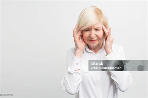 아픈 고 오래 된 여자는 그녀가 두통을 보여주는 그녀의 머리를 만지고 있다 아마 그녀는 아픈 얻을 것 이다 닫습니다 흰색 배경에