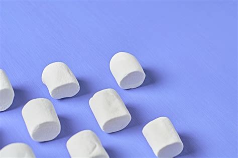 흰색 마시멜로 원통형 형태의 행은 보라색 긁힌 콘크리트 테이블에 놓여있다 텍스트를 위한 공간 개체 그룹에 대한 스톡 사진 및