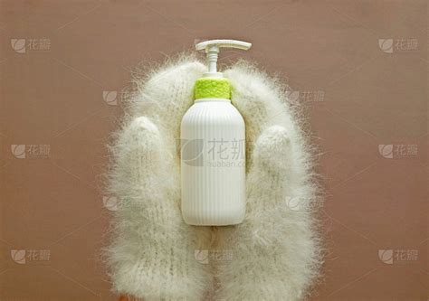 化妆品泵瓶保湿乳液手在手套在柔和的背景。白色波纹瓶表面皂液泵。冬季手部护肤乳液。