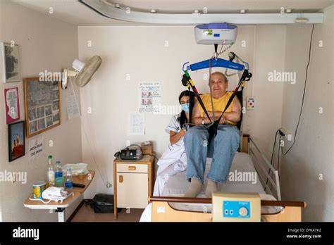 Caregiver Preparing The Bedtime Of A Disabled Patient In His Room At The Retirement Home Stock
