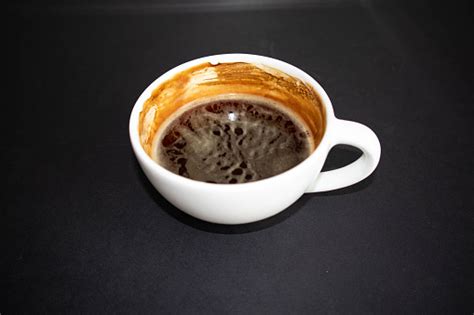 검은 색 배경에 향기로운 갓 갈은 아라비카 커피의 화이트 컵 컵은 접시에 있습니다 검은 색 배경에 향기로운 갓 갈은 아라비카