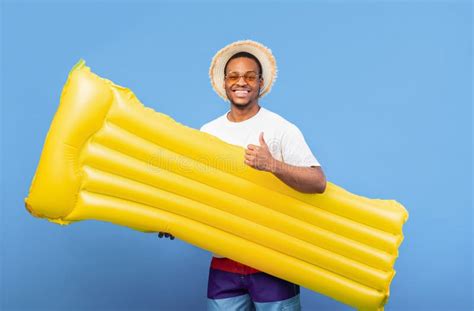 Young Black Guy In Summer Wear And Straw Hat Holding Yellow Inflatable Lilo And Showing Thumb Up