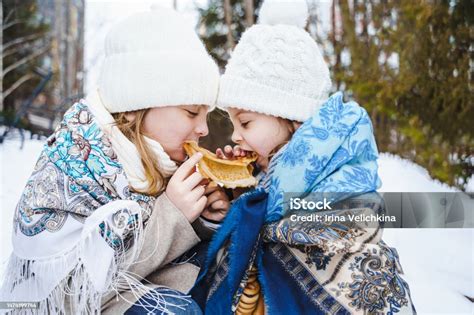 러시아 국가 축제 마슬레니차 슈로브타이드 머리 스카프에 작은 귀여운 아름다운 소녀는 큰 맛있는 팬케이크를 먹고 겨울 팬케이크