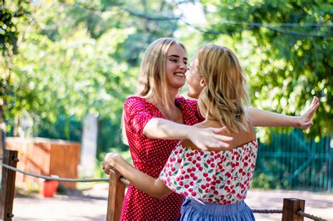 Two Attractive Blonde Girlfriends Talking And Hugging In The Park