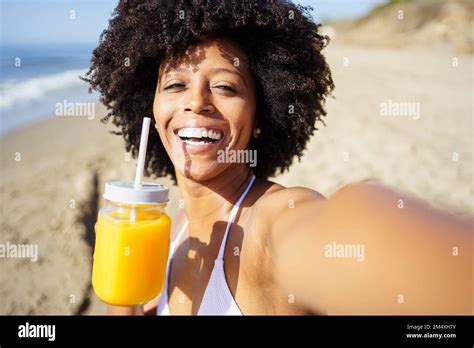 Happy Woman Taking Selfie With Orange Juice At Beach In Summer Stock