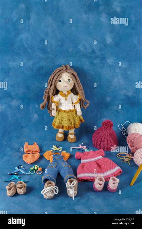 A Cute Amigurumi Doll Handmade On A Blue Background With Clothes And
