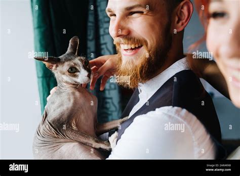 Newly Wed Couple Standing Next To The Window Cuddling Their Hairless