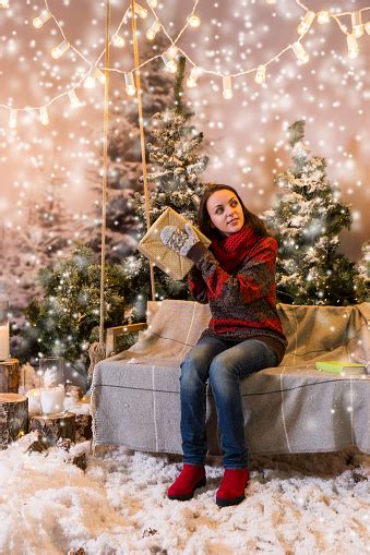 예쁜 여자는 손전등 아래 담요와 함께 그네에 앉아서 눈 덮인 공원에 있는 선물 상자를 떨고 가문비나무에 대한 스톡 사진 및 기타 이미지 가문비나무 겨울 계절 Istock