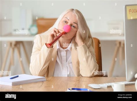 Funny Mature Woman With Clown Nose And Party Whistle In Office April