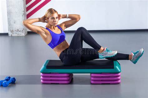 Woman Sitting On Step Platform And Doing Press Aerobic Having Work Out In Fitness Club Stock