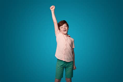 웃는 어린 소년이 손을 들고 푸른 색 벽 배경에 고립된 승리를 즐기고 있다 흥분 쾌활한 파란색 배경입니다 행복한 가족 아이에 대한 스톡 사진 및 기타 이미지 Istock