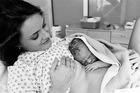 Feliz mamá teniendo su bebé piel a piel los primeros segundos después del parto
