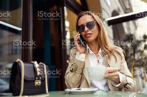 선글라스를 끼고 카페 테라스에 앉아 커피를 마시며 전화 통화를 하는 아름다운 여자 25 29세에 대한 스톡 사진 및 기타 이미지 25 29세 개념 건물 외관 Istock