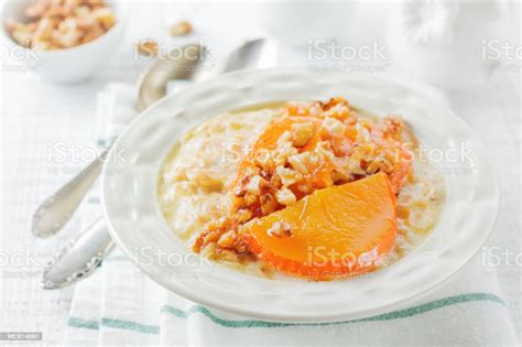 캐 러 멜된 감 및 흰색 나무 배경에 빛 세라믹 그릇에 호두와 오트밀 죽 선택적 초점입니다 최고의 볼 수 있습니다 공간에 복사