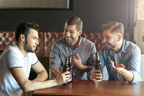 Tres amigos hablando juntos mientras beben cerveza en el café Foto