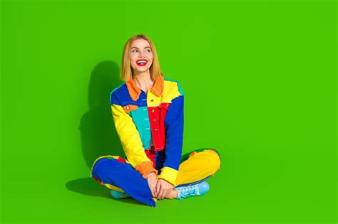 활기찬 여러 가지 빛깔의 데님 차림을 입은 쾌활한 젊은 여자가 즐거운 표정으로 녹색 배경에 앉아 있습니다 20 24세에 대한 스톡 사진 및 기타 이미지 Istock